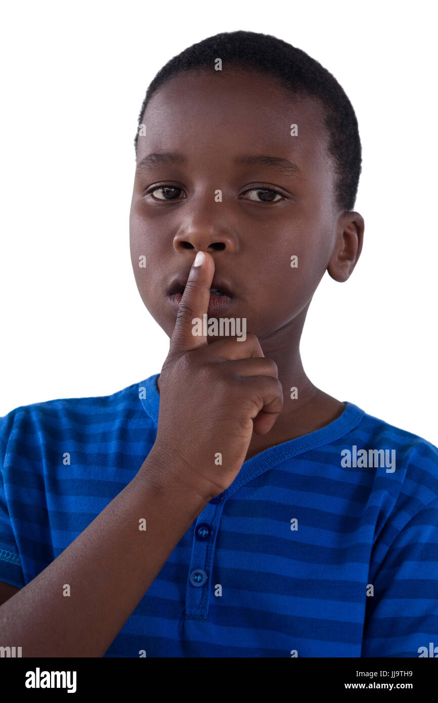 Portrait of boy with finger on lips against white background Stock ...