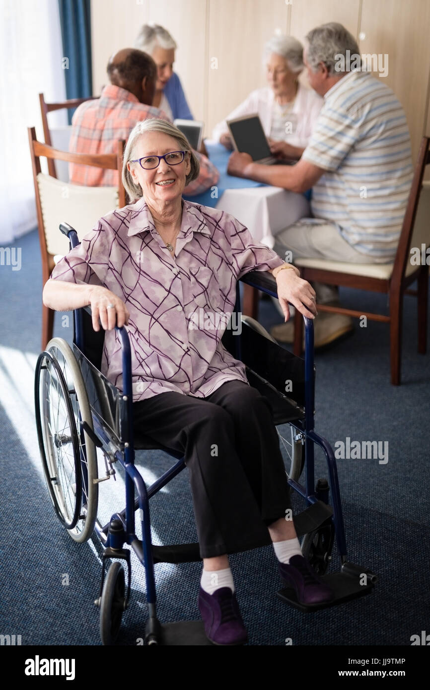 Portrait of smiling disabled senior woman sitting on wheelchair against ...