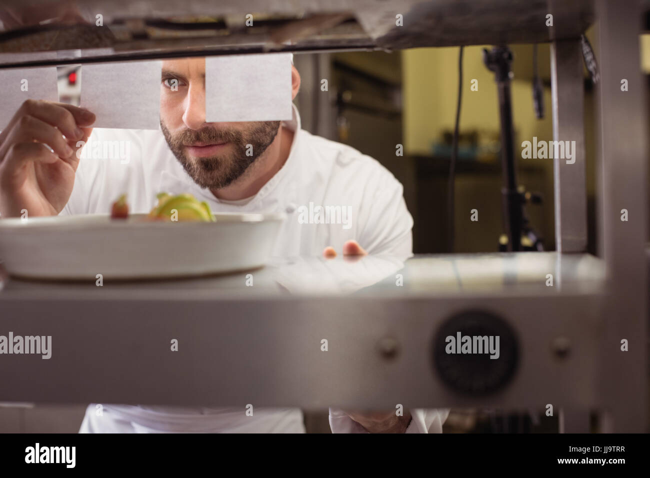 Chef reading his order on sticky note in kitchen counter at restaurant ...