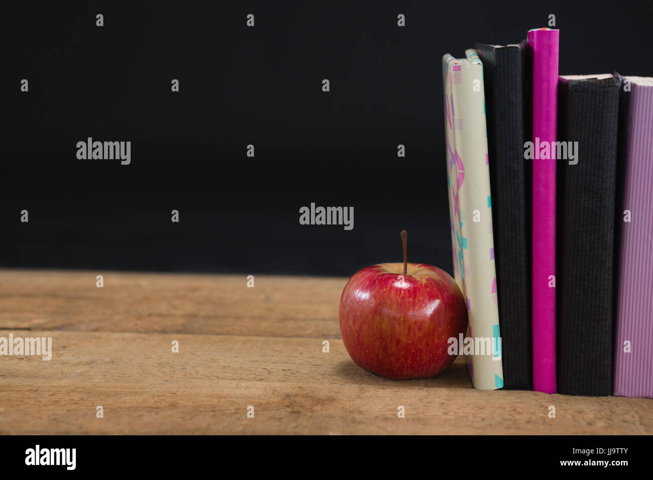 Apple and books on wooden table against black background Stock Photo ...