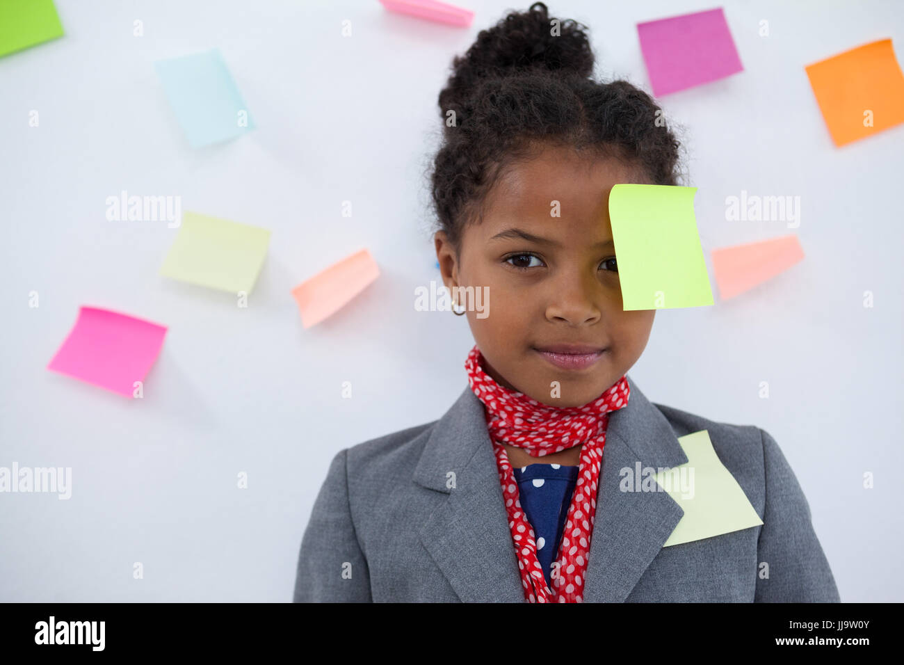 Portrait of businesswoman with sticky notes stuck on head standing ...