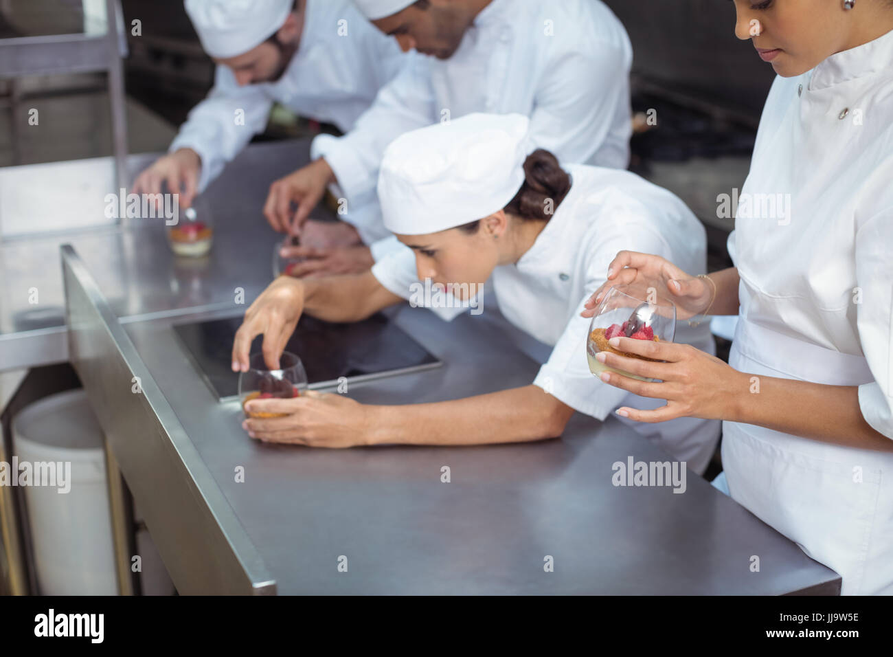 Attentive chefs finishing dessert in glass at restaurant Stock Photo ...