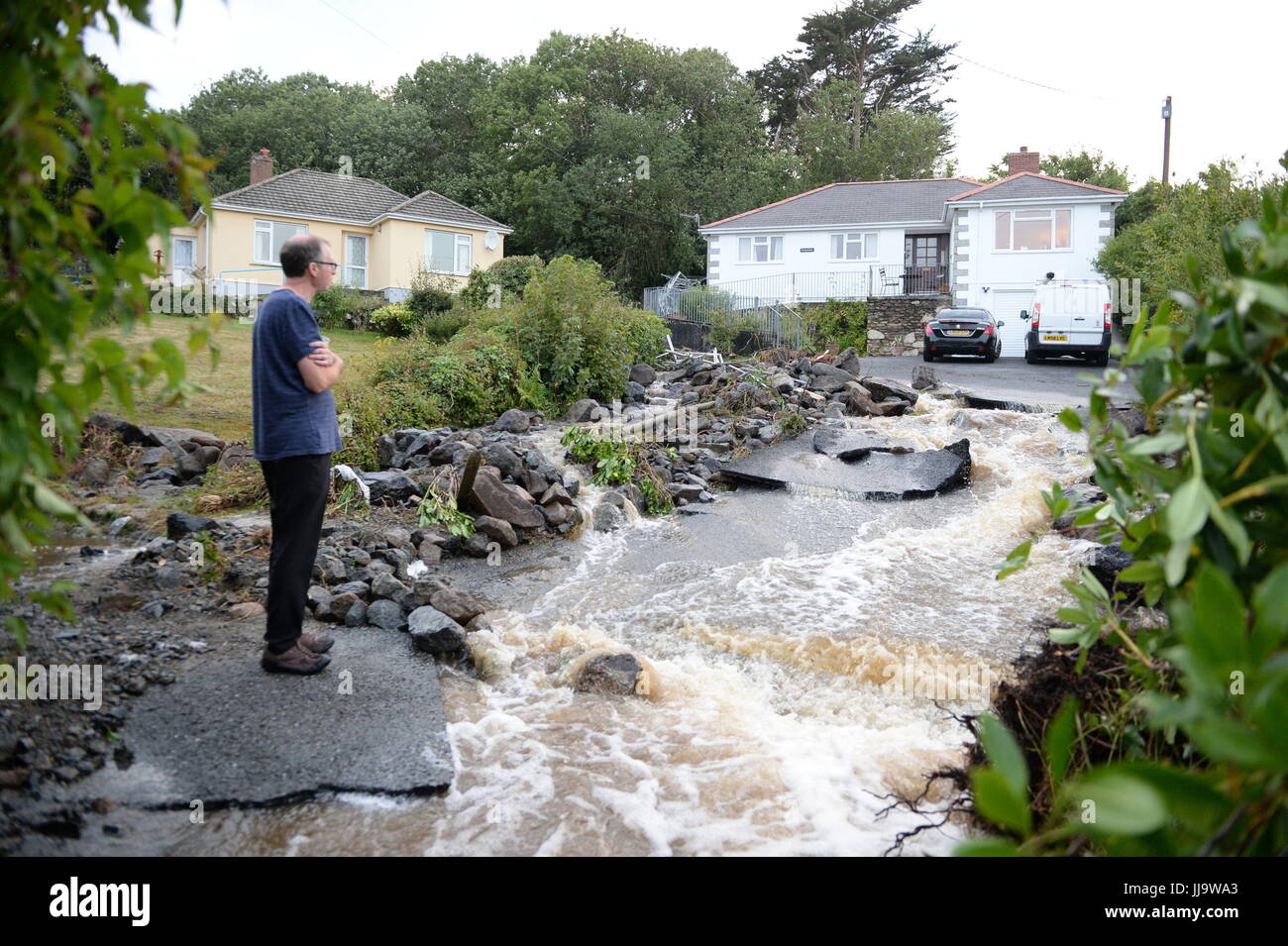 A man looks at a damaged driveway caused by water from flash flooding ...