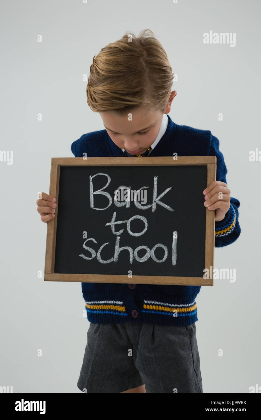 Adorable schoolboy holding slate with text against white background ...