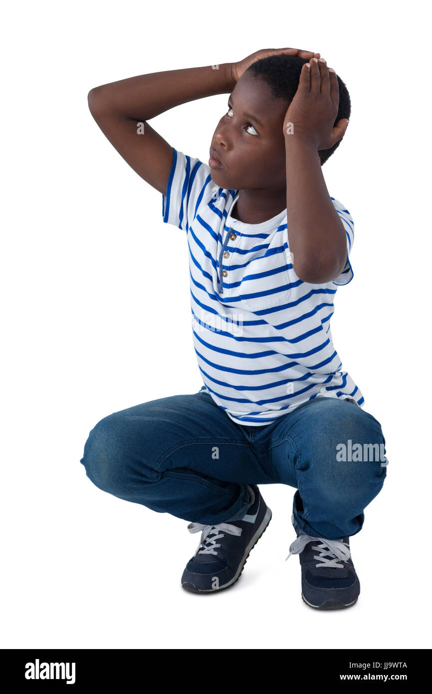 Sad boy crouching with hand on head against white background Stock ...