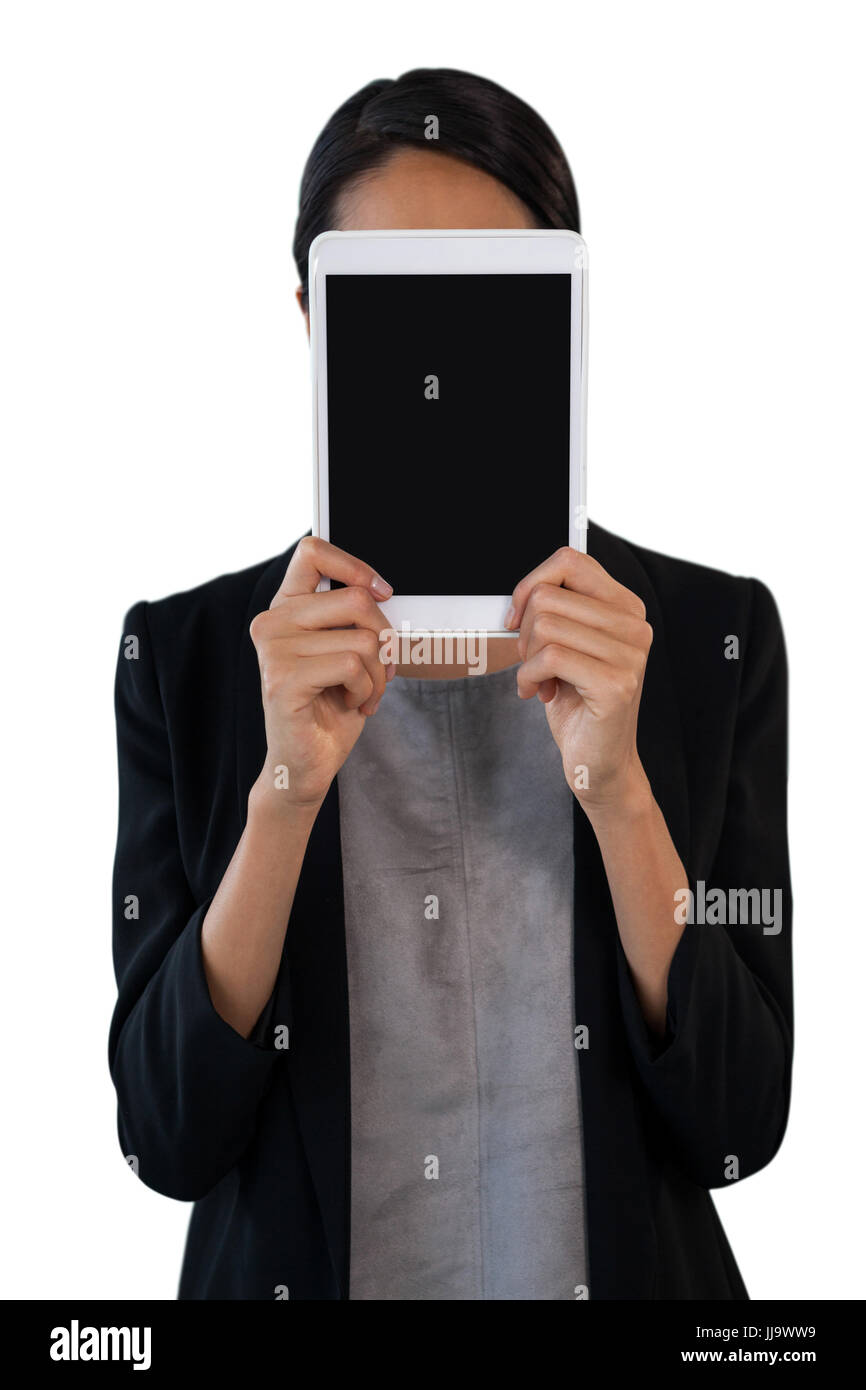 Businesswoman holding tablet computer in front of face while standing ...
