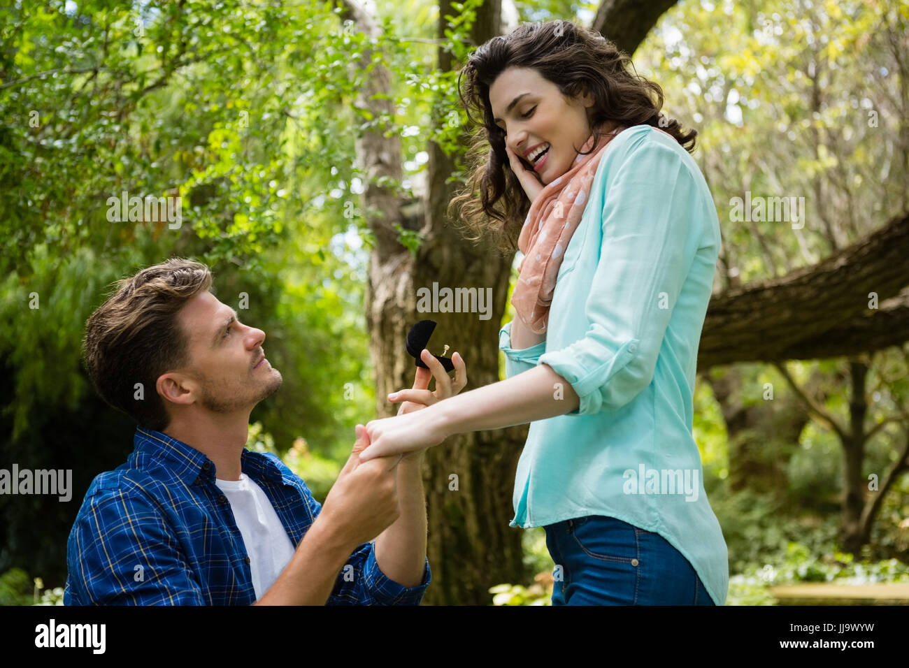 Handsome man proposing woman by gifting ring in garden Stock Photo - Alamy