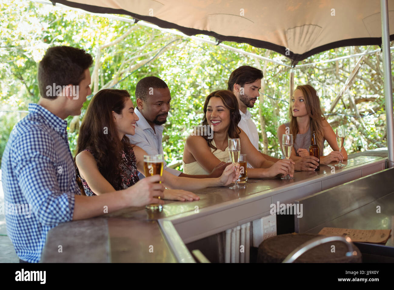 Smiling friends interacting while having a alcohol at counter Stock ...
