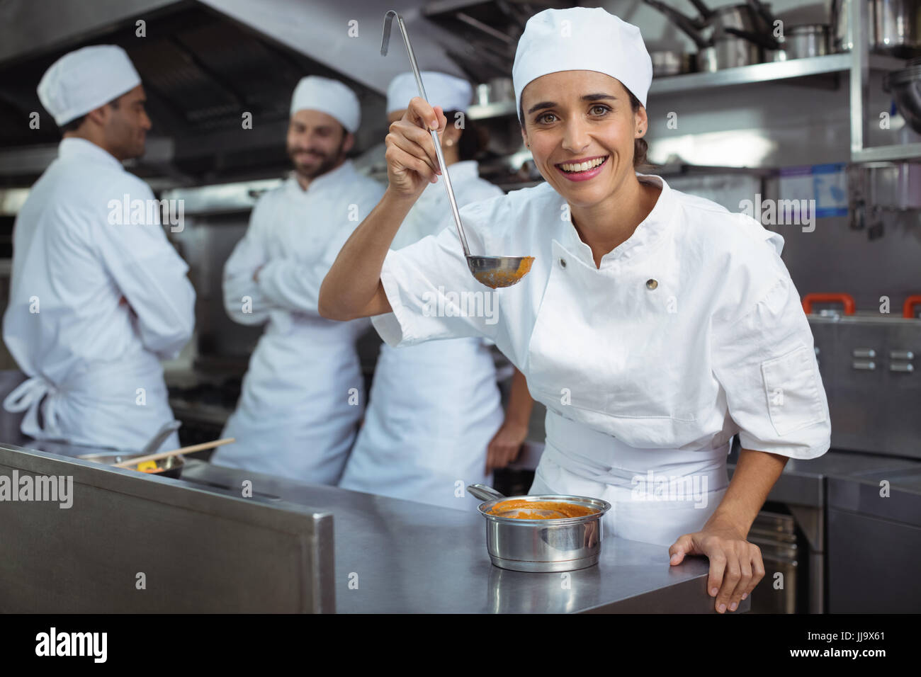 Portrait of chef tasting food from spoon in kitchen at restaurant Stock ...
