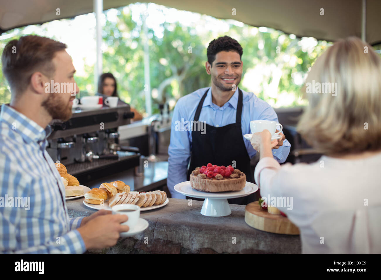Waiter serving coffee to customer at counter in restaurant Stock Photo ...