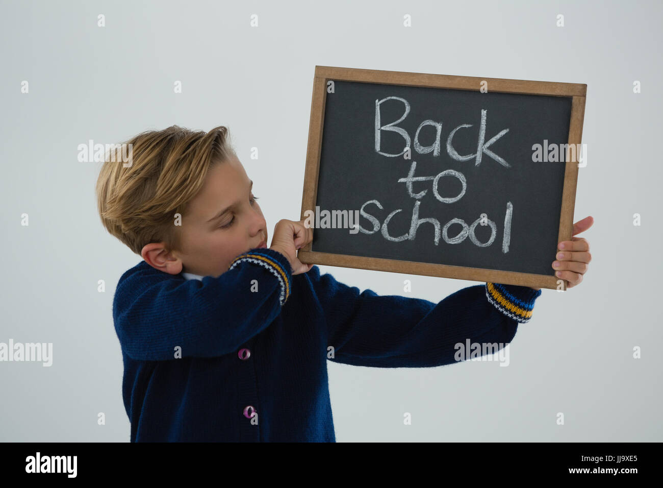 Portrait of schoolboy holding slate with text against white background ...