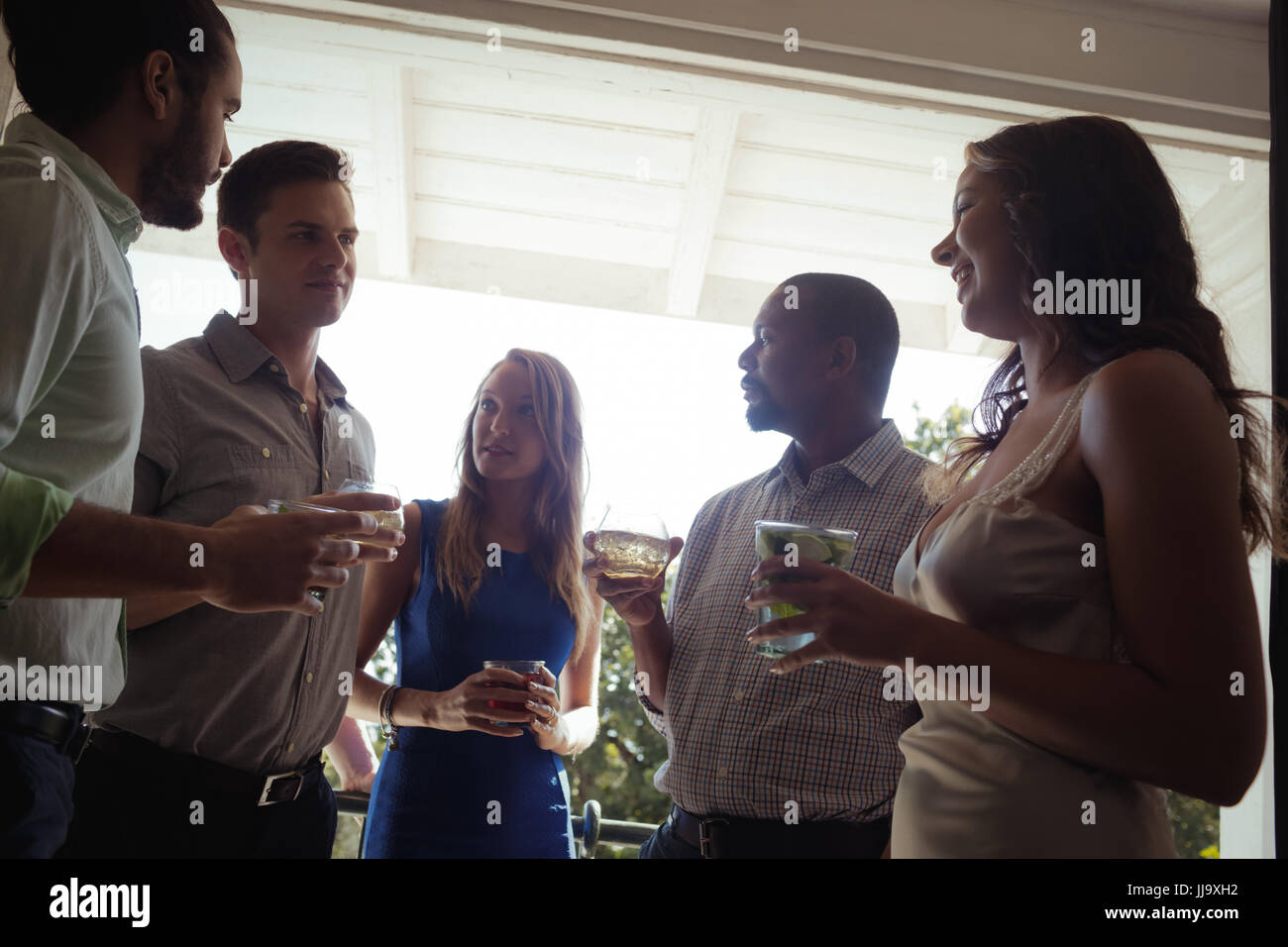 Group of friends interacting with each other while having cocktail ...