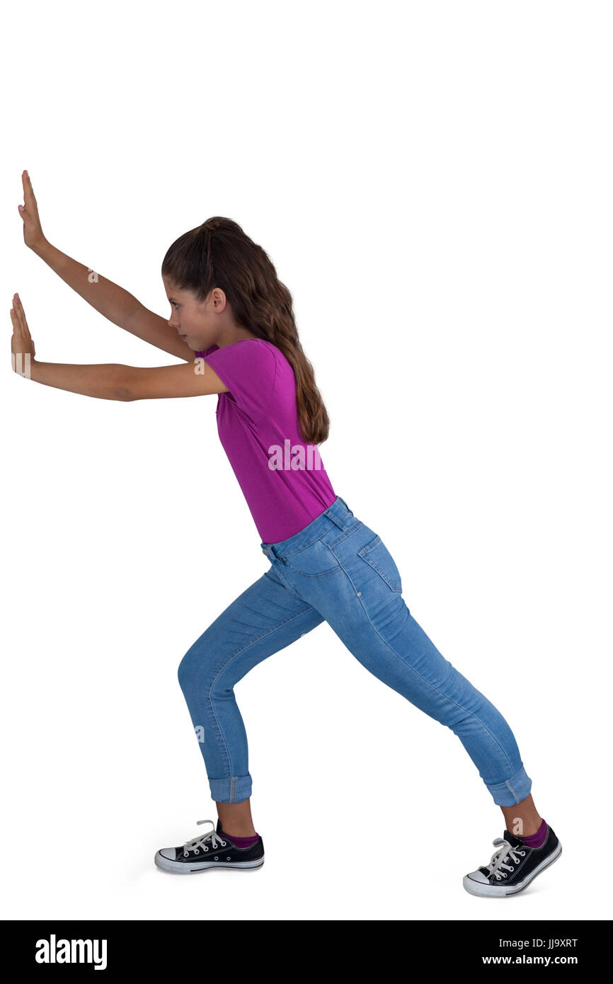 Side view of girl pushing against white background Stock Photo - Alamy