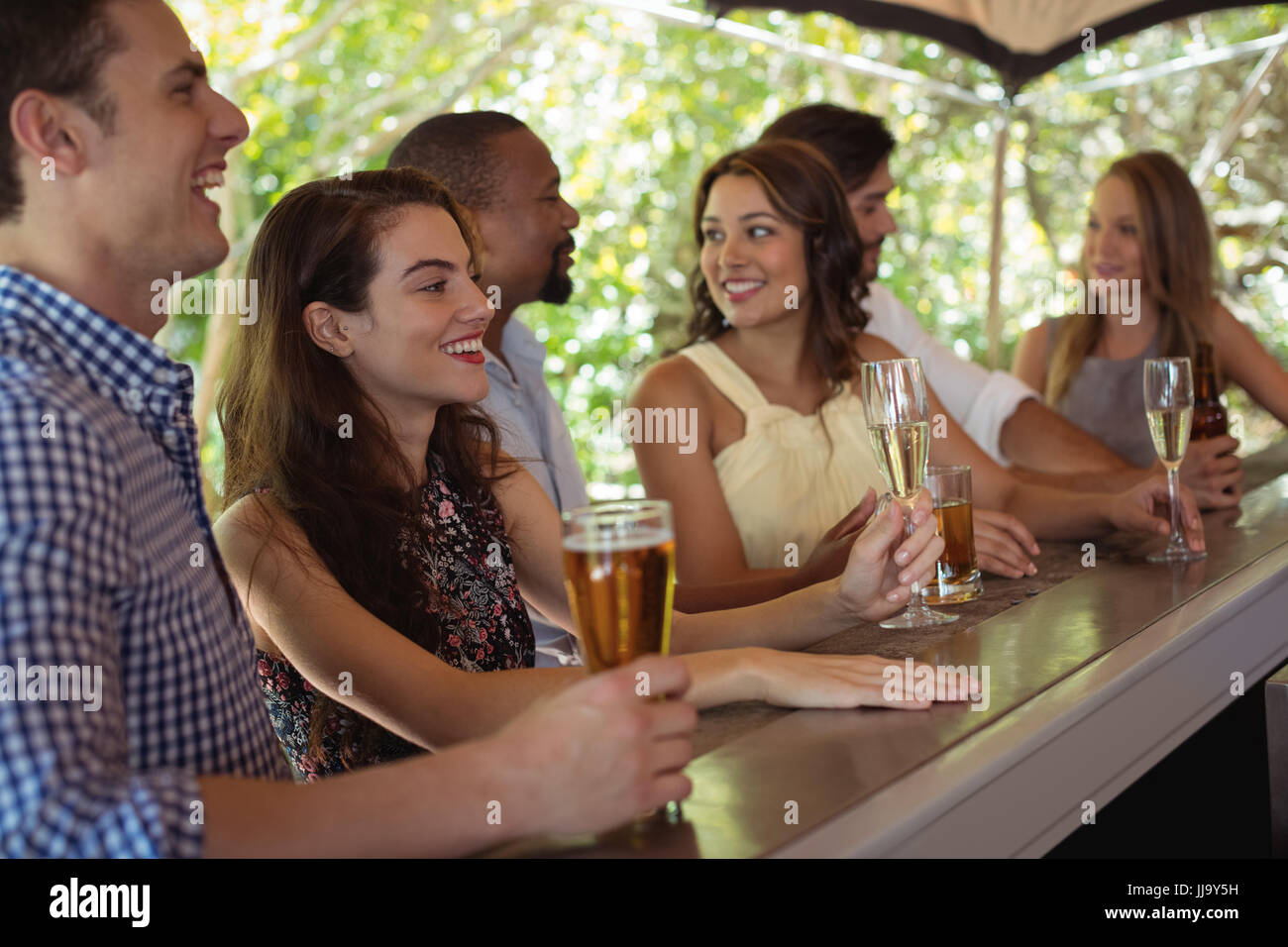 Smiling friends interacting while having a alcohol at counter Stock ...