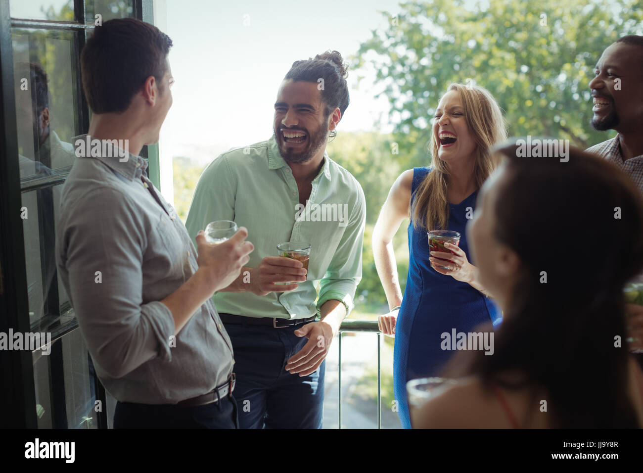 Group of friends interacting with each other while having cocktail ...