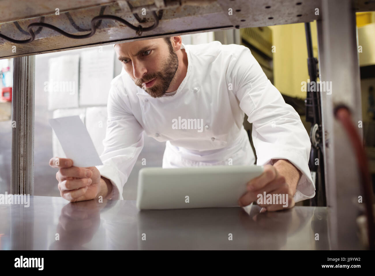 Chef reading his order on sticky note in kitchen counter at restaurant ...