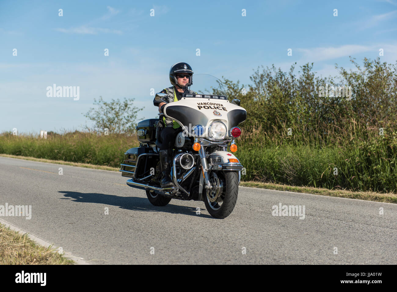 Police motorcyclist riding down the roadway Stock Photo - Alamy