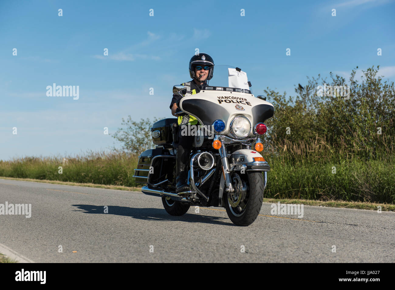 Police motorcyclist riding down the roadway Stock Photo - Alamy