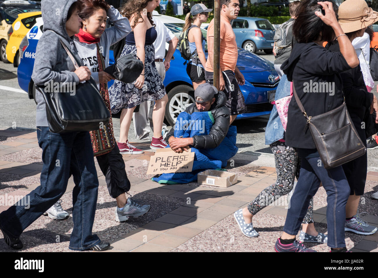 Homeless Man sitting on sidewalk with "Please Help" sign asking for ...