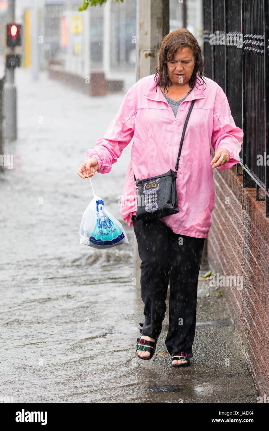 A woman walks through flash flooding water on her way home after heavy ...