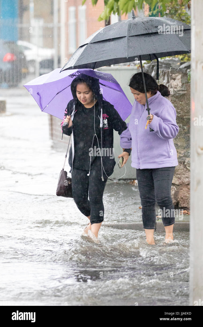 Two woman walking through flash flooding water on their way home after ...