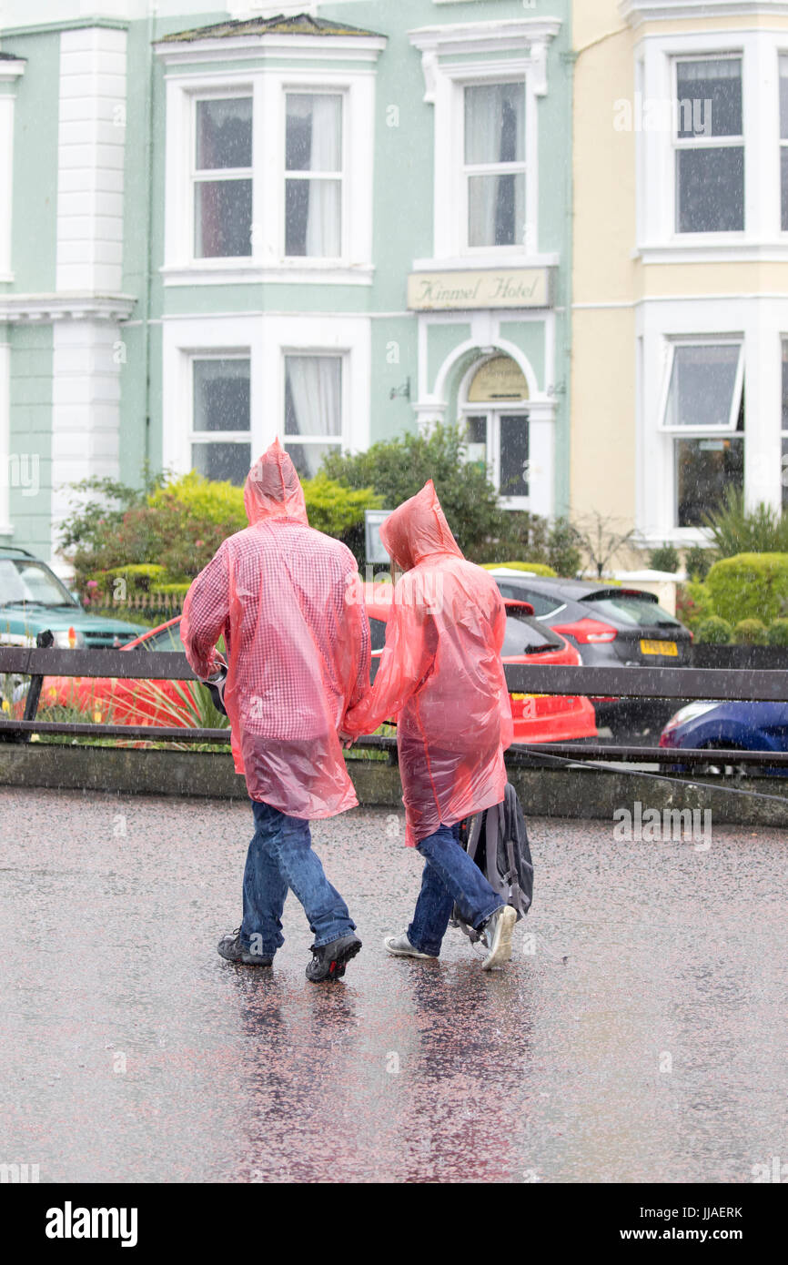 A couple in rain weather clothing braving the torrential rain on the ...