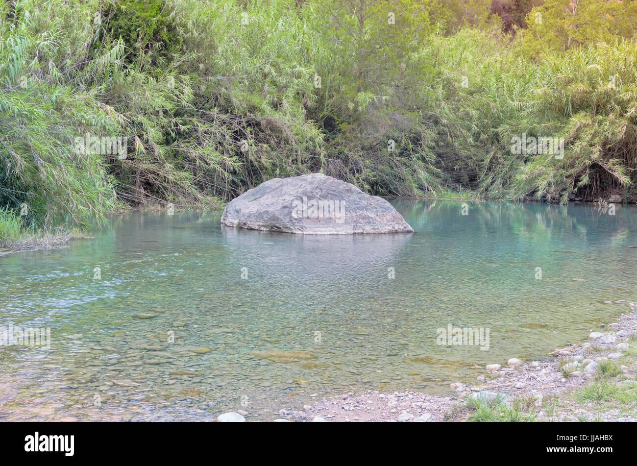 Mijares river with clear waters and big rock in the middle. Thermal ...