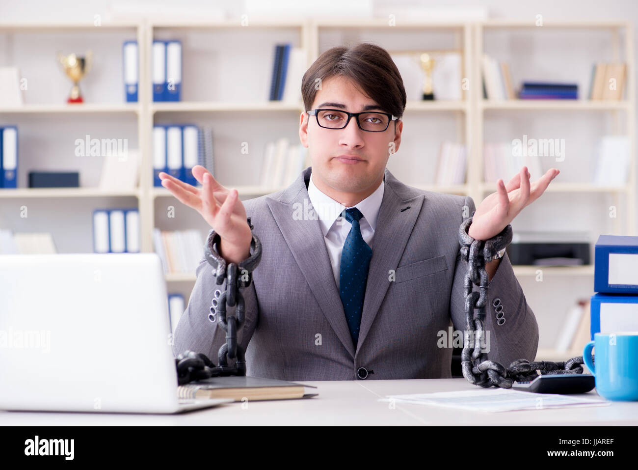 Businessman tied with chains to his work Stock Photo - Alamy