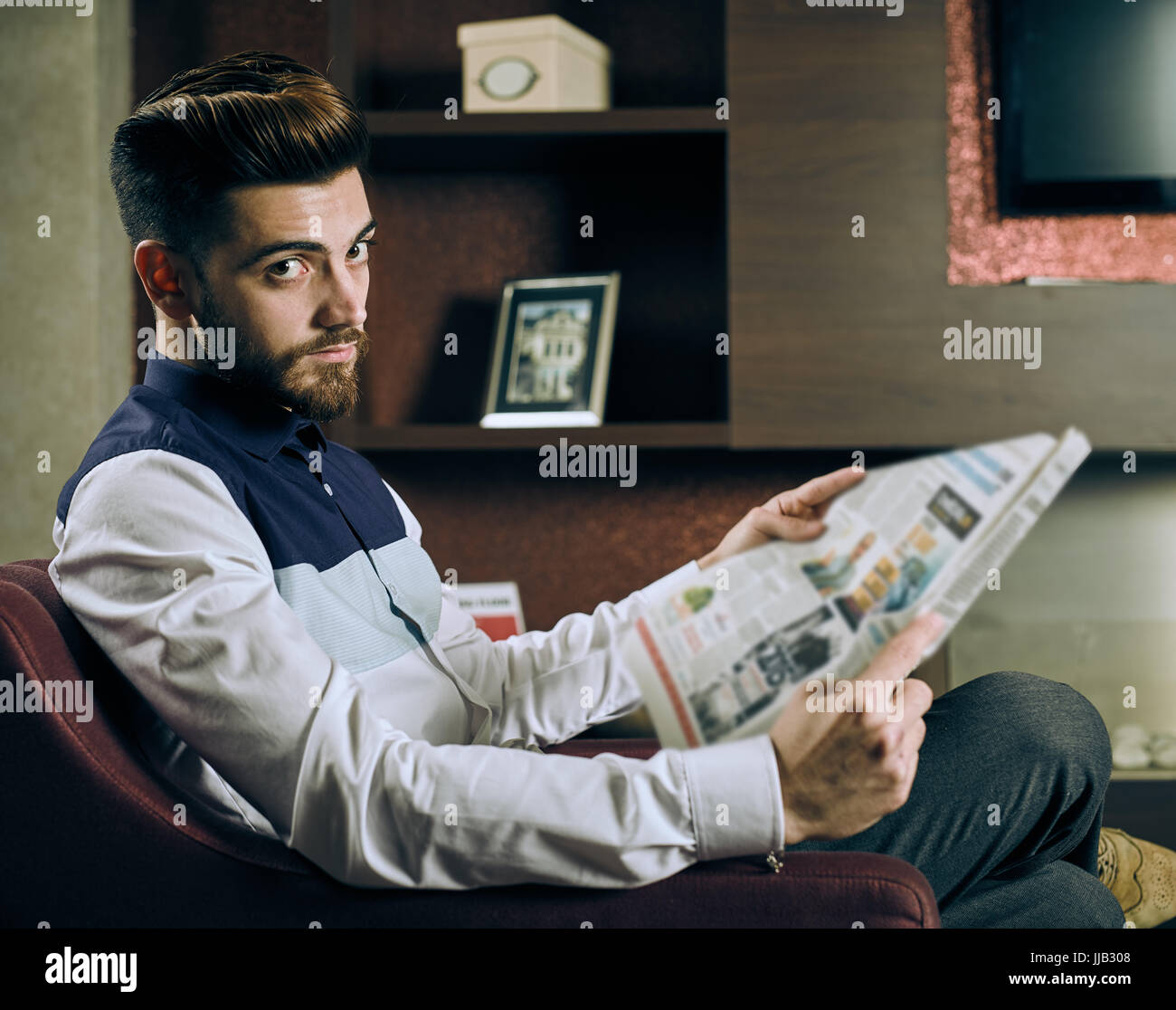Young man reading newspaper in the livingroom Stock Photo - Alamy