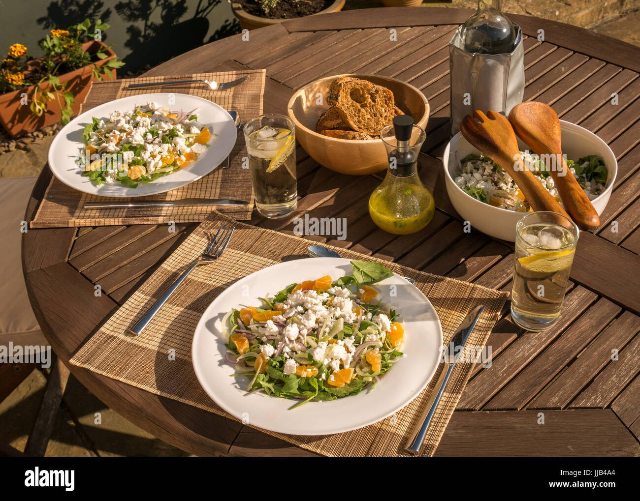 Summer salad served outside on garden patio deck table with clementines ...