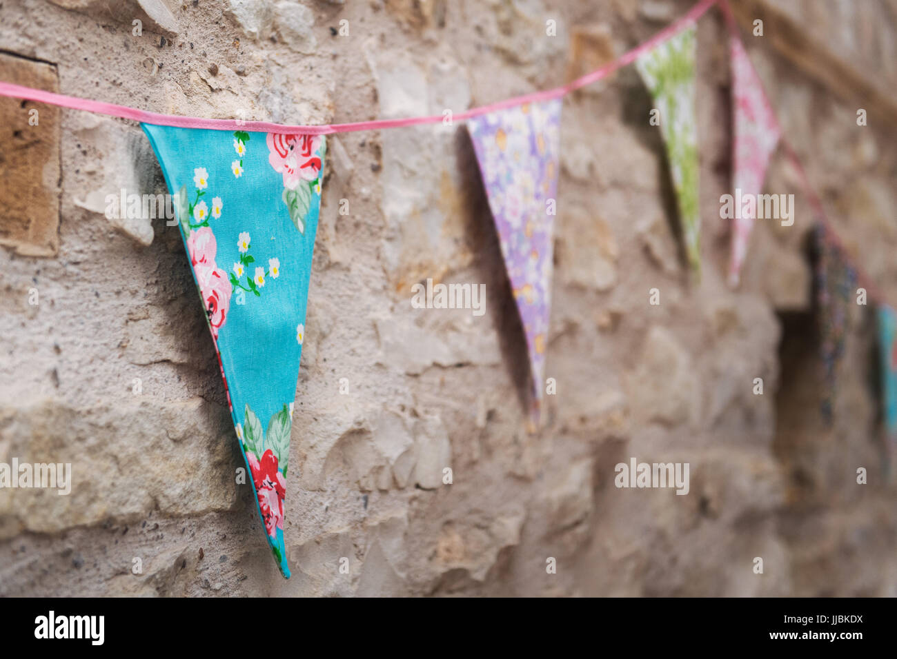 Colourful pastel bunting on the wall of a rustic barn wedding reception ...