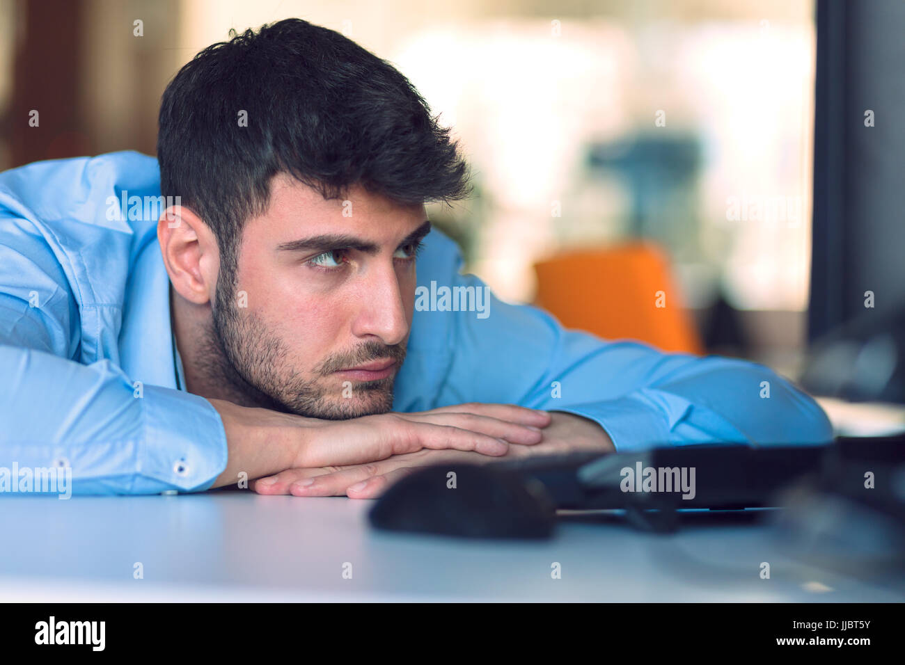 Portrait of a depressed office worker laying on his desk and thinking ...
