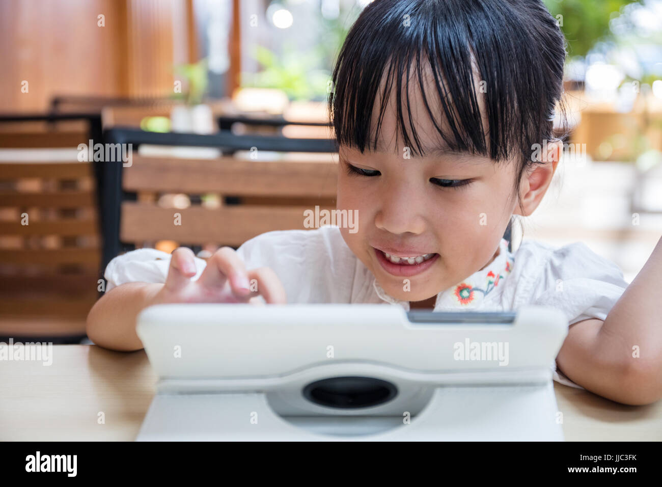 Asian Chinese little girl playing tablet computer at outdoor cafe Stock ...
