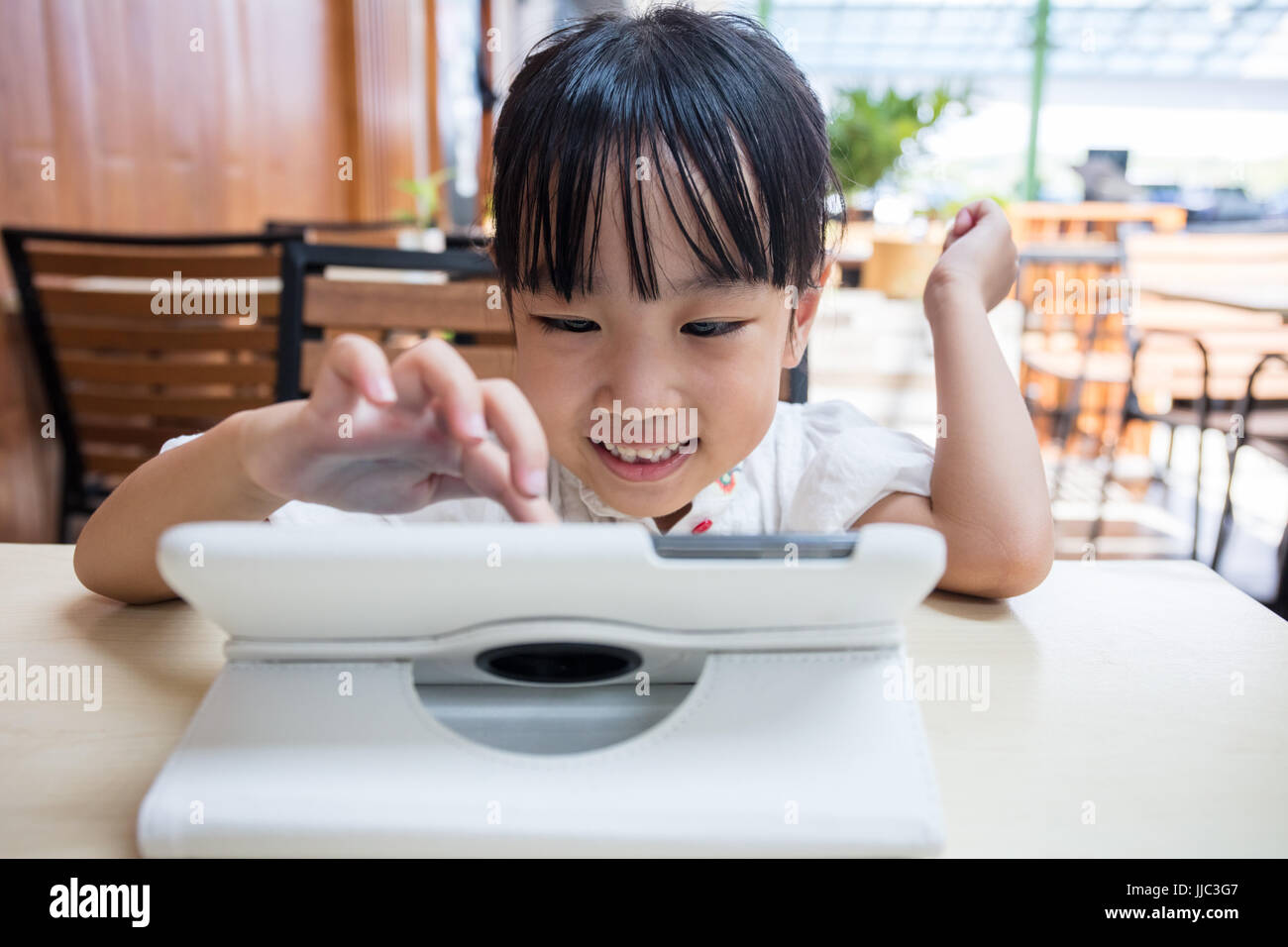 Asian Chinese little girl playing tablet computer at outdoor cafe Stock ...