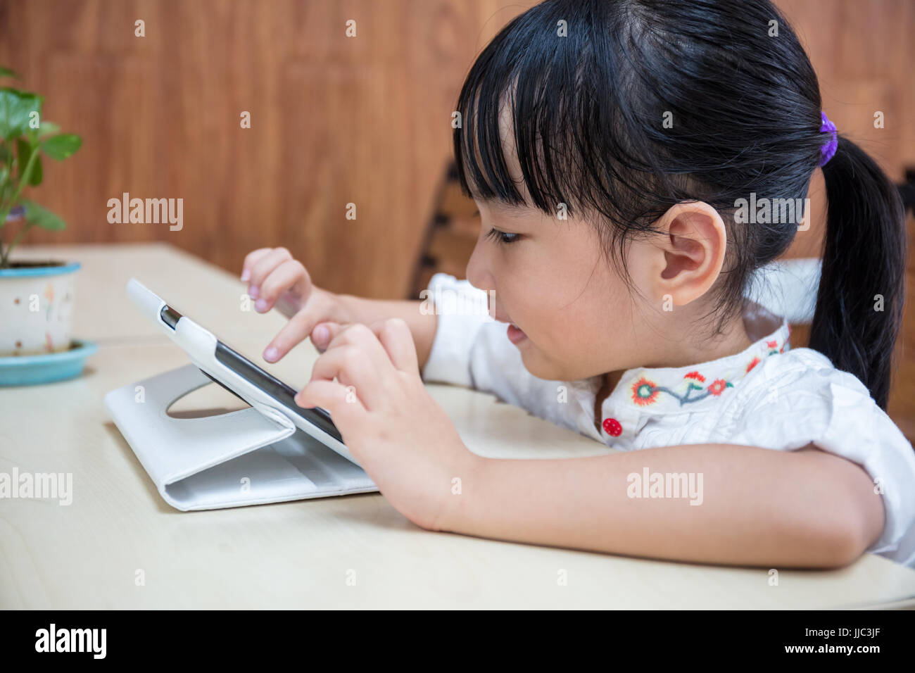 Asian Chinese little girl playing tablet computer at outdoor cafe Stock ...