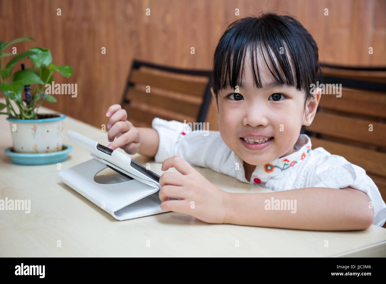 Asian Chinese little girl playing tablet computer at outdoor cafe Stock ...