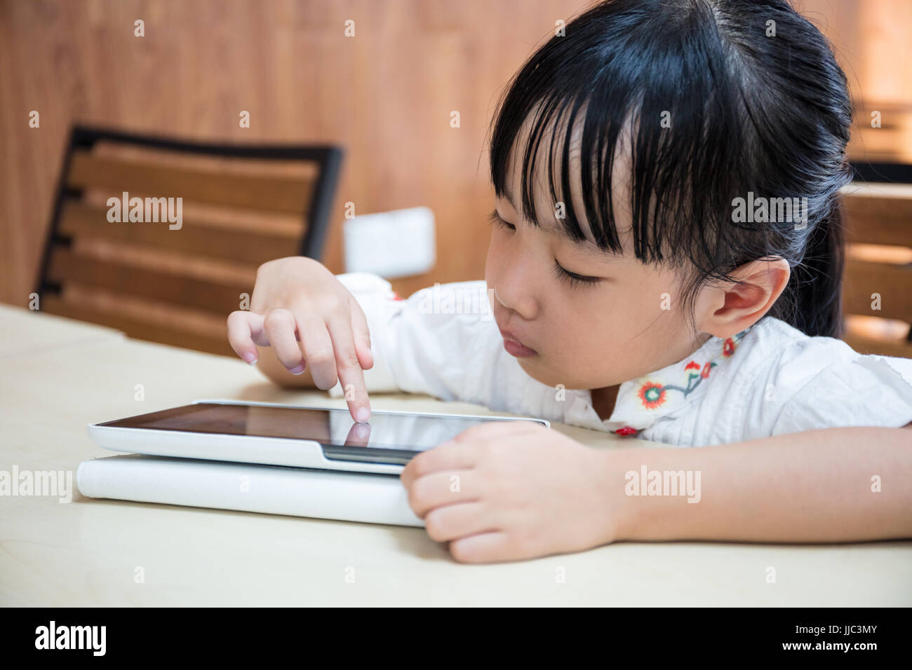 Asian Chinese little girl playing tablet computer at outdoor cafe Stock ...