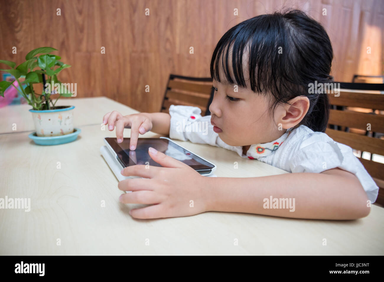 Asian Chinese little girl playing tablet computer at outdoor cafe Stock ...