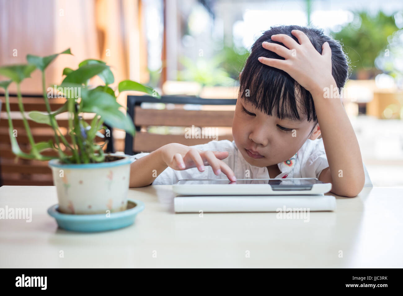 Asian Chinese little girl playing tablet computer at outdoor cafe Stock ...