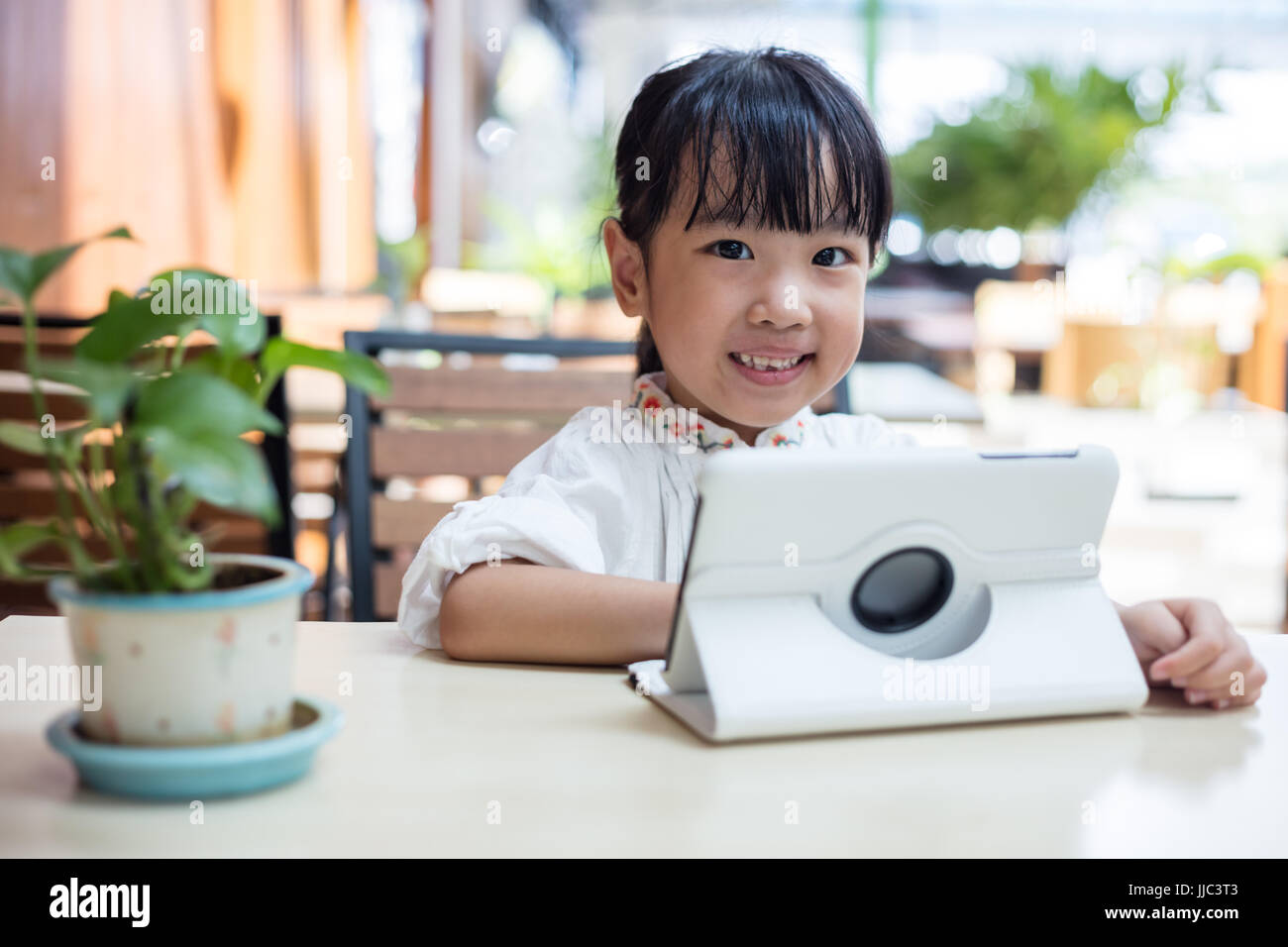 Asian Chinese little girl playing tablet computer at outdoor cafe Stock ...