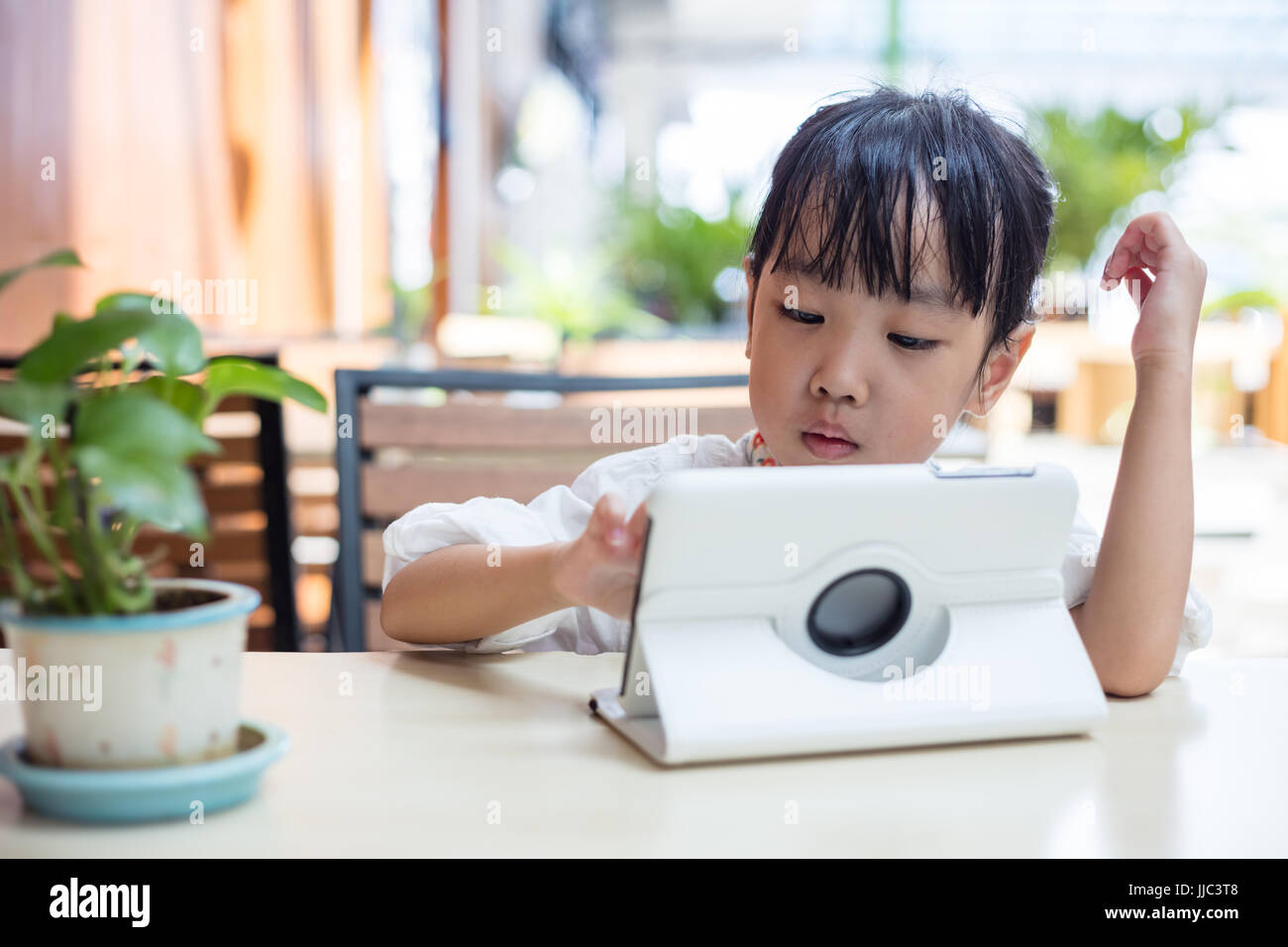 Asian Chinese little girl playing tablet computer at outdoor cafe Stock ...