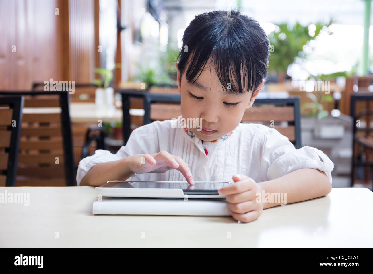 Asian Chinese little girl playing tablet computer at outdoor cafe Stock ...