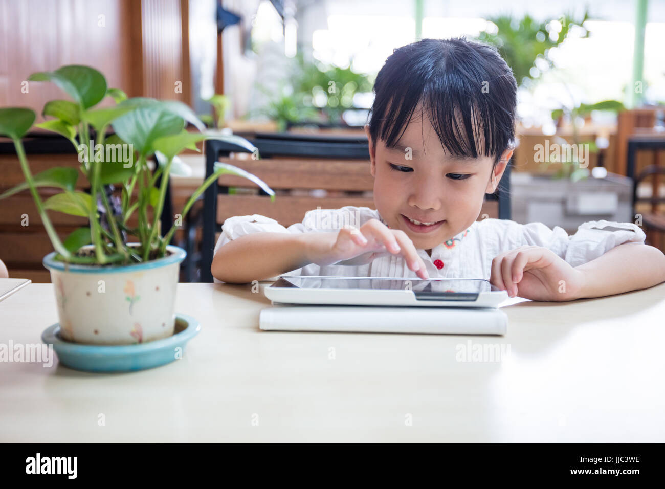 Asian Chinese little girl playing tablet computer at outdoor cafe Stock ...