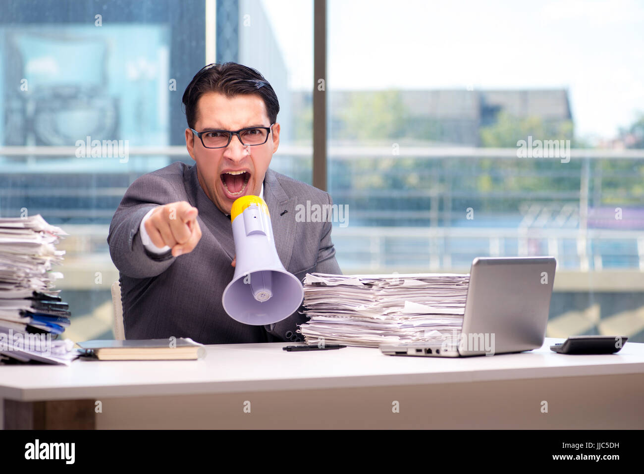 Angry businessman with loudspeaker in the office Stock Photo - Alamy
