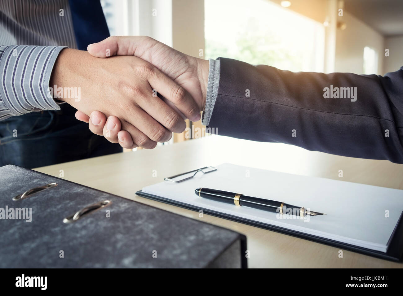 Midsection of a businessman shaking hands with a cropped female ...