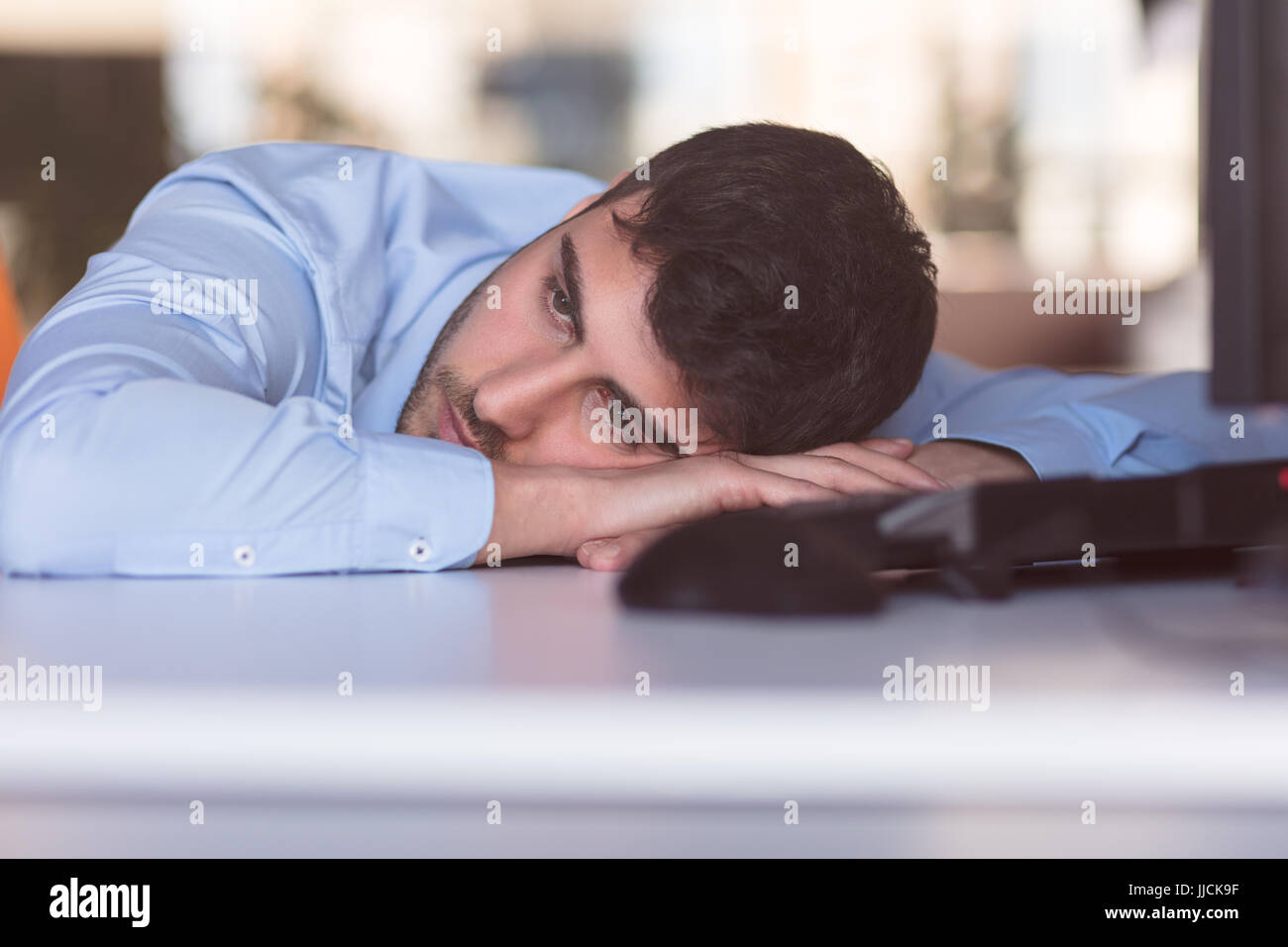Portrait of a depressed office worker laying on his desk and thinking ...