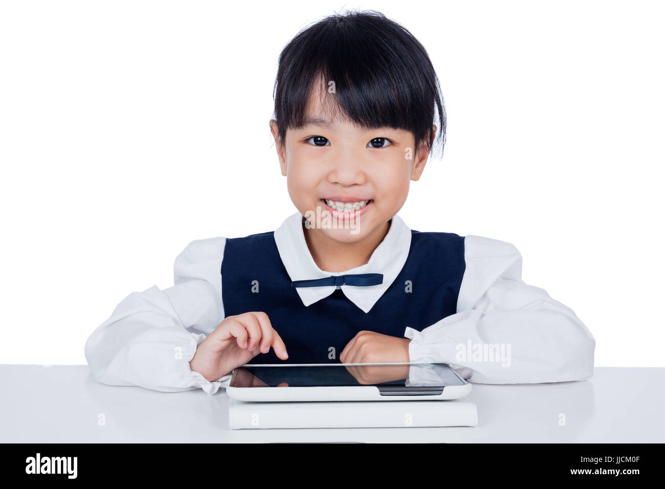 Asian Chinese little girl in uniform playing with tablet computer in ...
