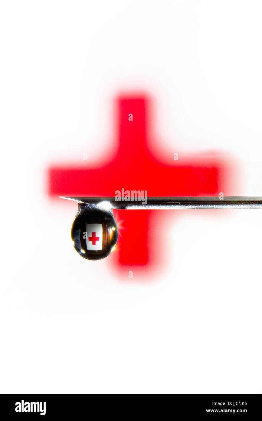 Reflection of a red cross in a drop of medication at the needle tip ...