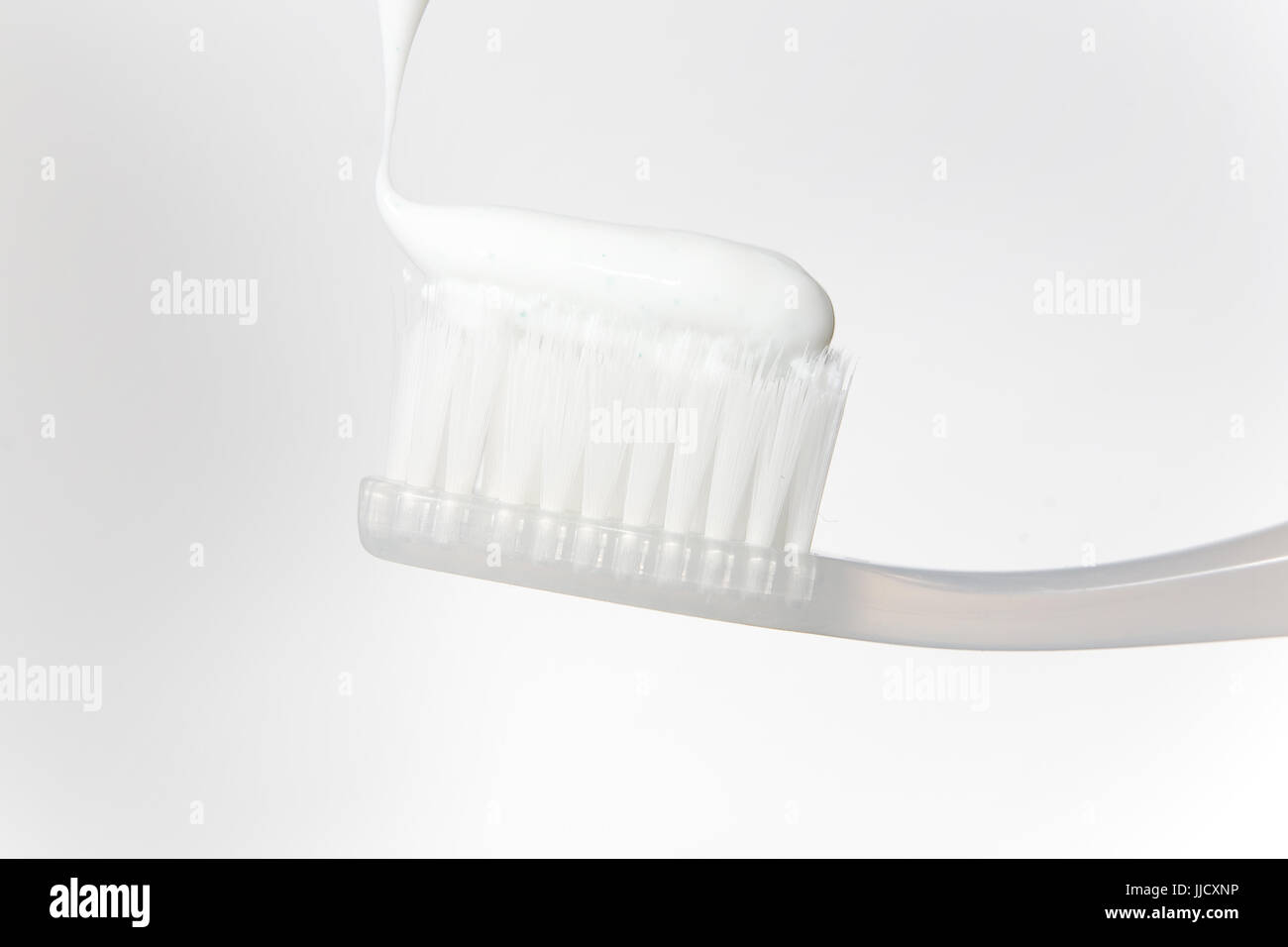 Hygiene products. White toothpaste on the toothbrush bright closeup ...