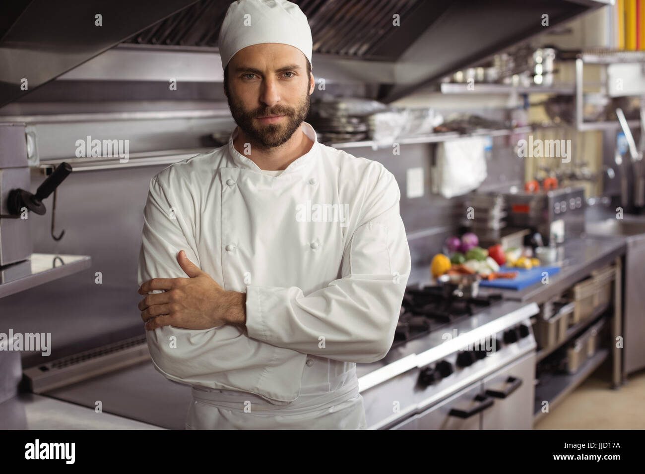 Portrait of confident chef standing with arms crossed in commercial ...